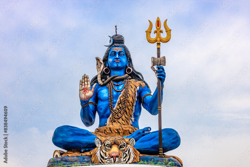 Blue statue of Lord Shiva and other hindu gods seated with a tiger skin ...