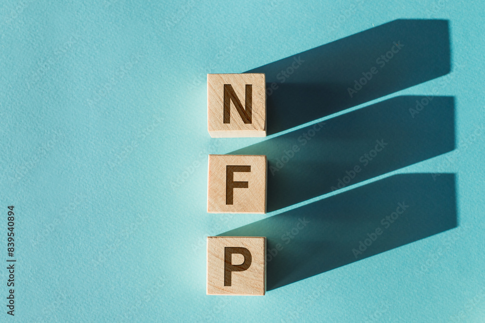 Word NFP - Non Farm Payrolls - acronym concept on cubes on a light blue ...