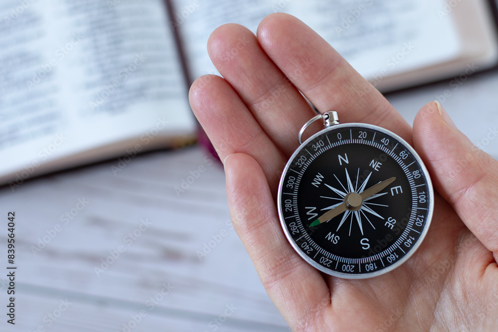 Hand holding compass on top of open holy bible book. Close-up. Guidance ...