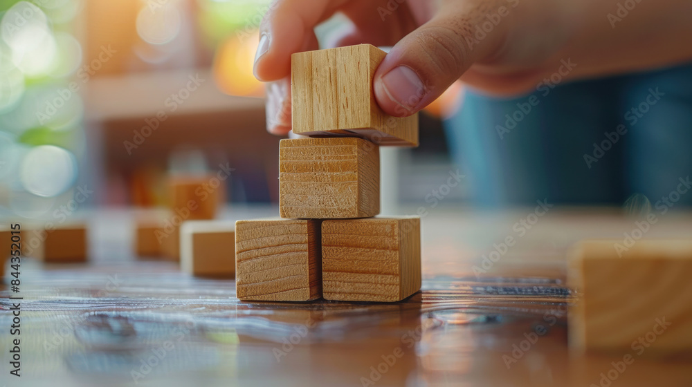 Close-up of a hand stacking wooden blocks, symbolizing teamwork ...