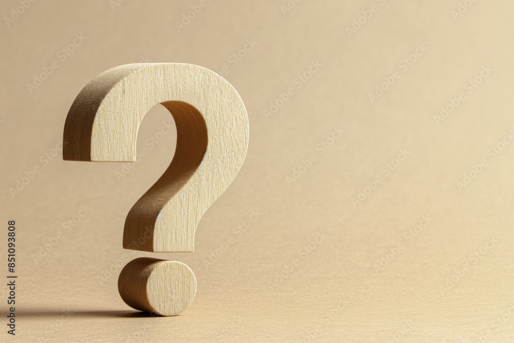 Solitary wooden question mark stands on a beige background, evoking a sense of mystery ...