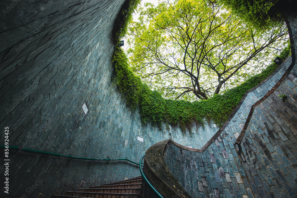 Empty spiral staircase of underground walkway. View of green tree in ...