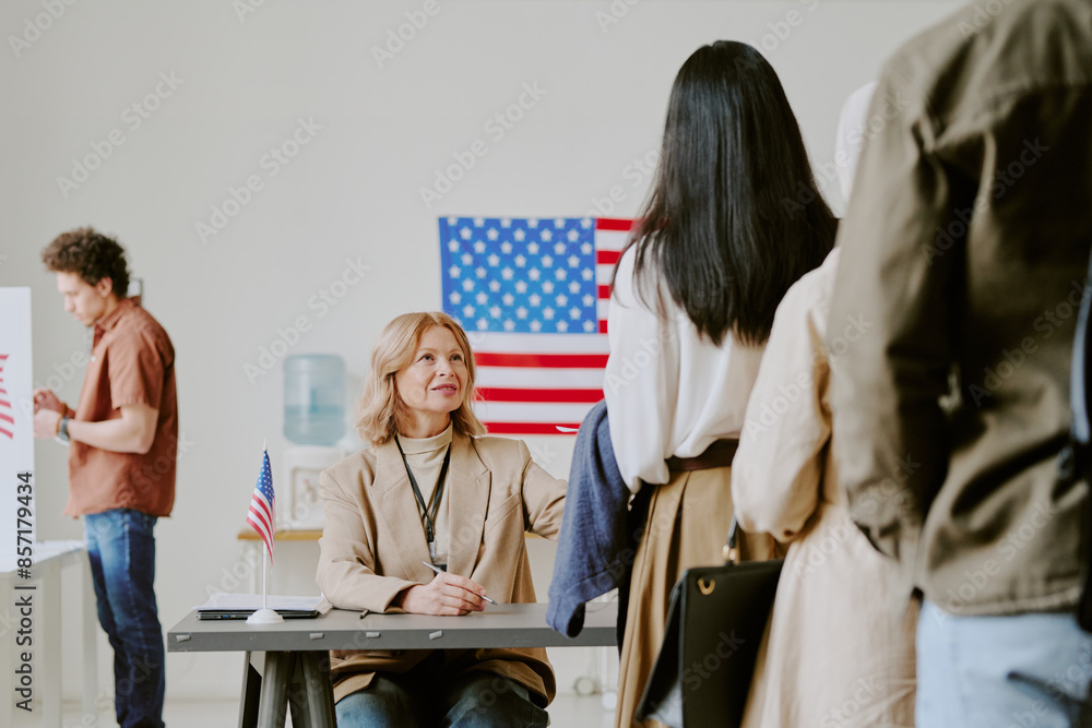 Mature Caucasian woman sitting at desk working at polling station on ...