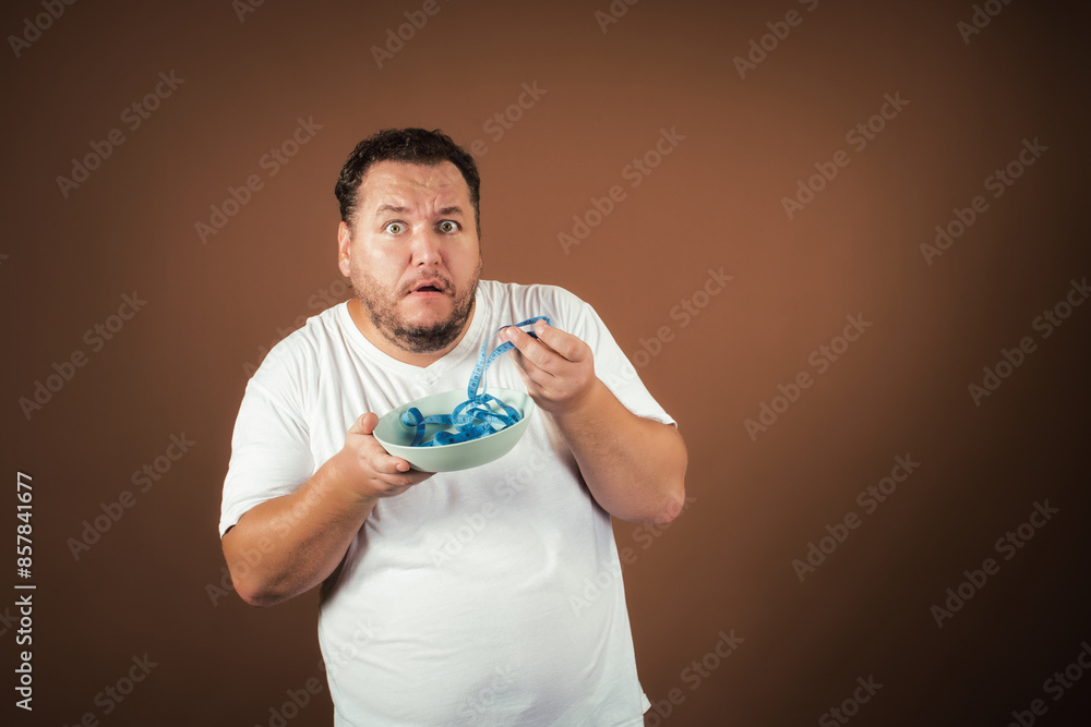Sports, diet and healthy lifestyle. Funny fat man posing on a brown ...