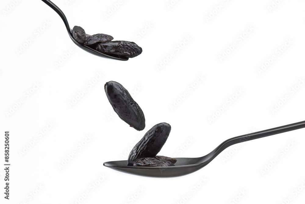 Falling Tonka beans from a spoon into a big spoon on a white background ...
