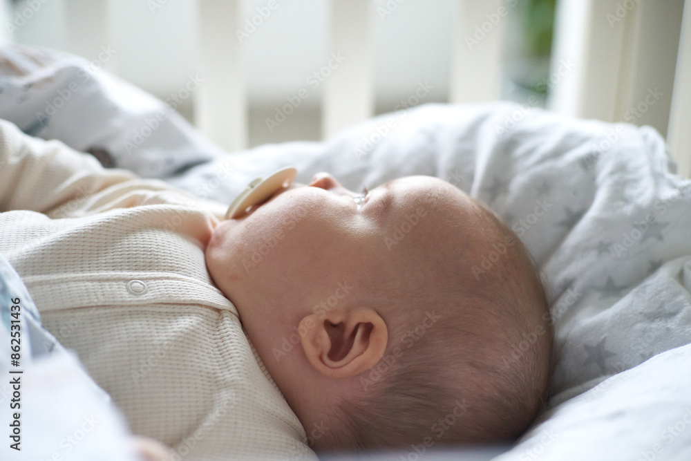 baby with pacifier in bed before sleep. Pretty six-month old baby boy ...