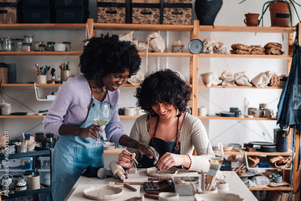 Diverse pottery class students designing clay work and drinking wine ...