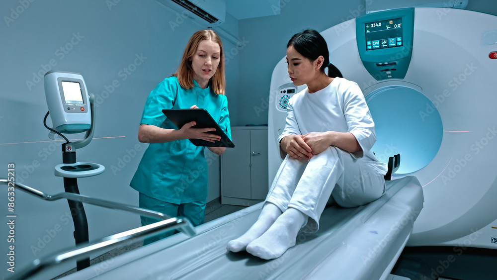 Doctor holding tablet and showing result of MRI. Patient lying at MRI ...