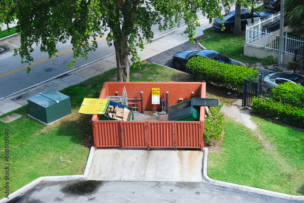 Dumpster half-filled with garbage next to residential area, road and ...
