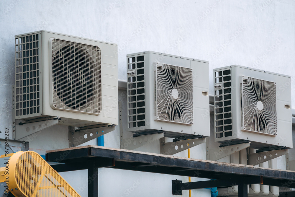 Air conditioner compressor installed on the wall of a building, along ...