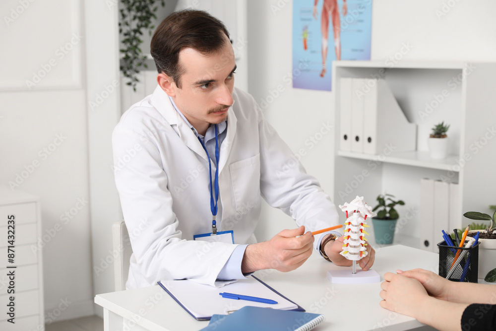 Male doctor explaining spinal anatomy with vertebral column model to ...