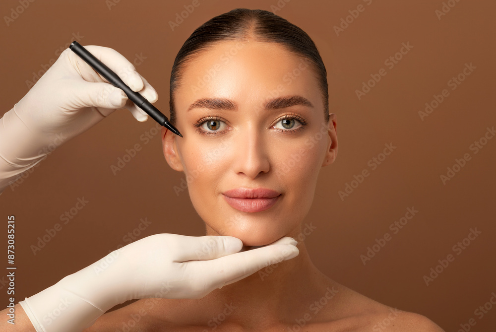 Beautician surgeon doctor hands drawing lines with pen on young woman ...