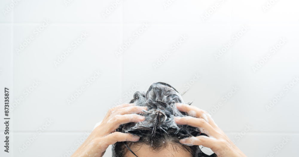 Young woman washing her hair with shampoo foaming. Female rubbing hair ...