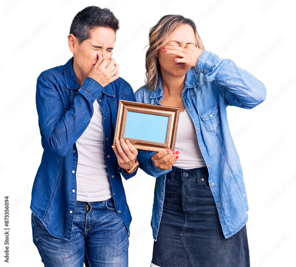 Couple of women holding empty frame smelling something stinky and ...