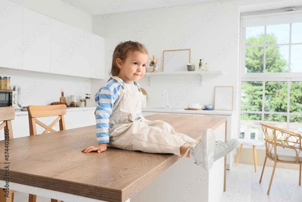 Cute little girl sitting on high table in kitchen. Child at risk Stock ...