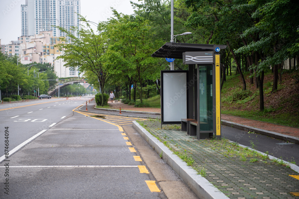 Bus stop and billboard in city with street trees and sidewalk blocks ...