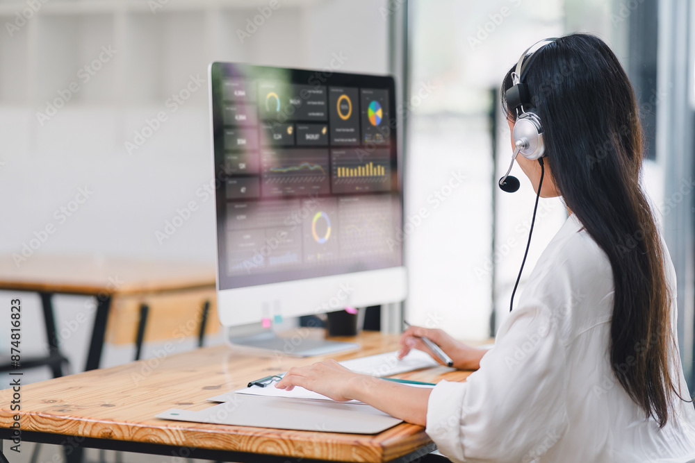 Customer service representative wearing headset analyzes data on ...