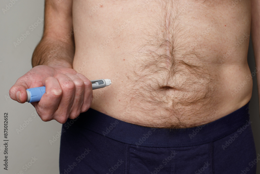 Man taking an insulin or semaglutide shot at home in his stomach ...