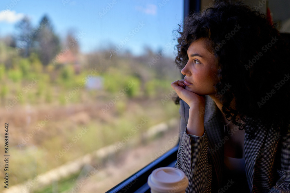 Contemplative woman enjoying the solitude of her train journey, looking out the window with a ...