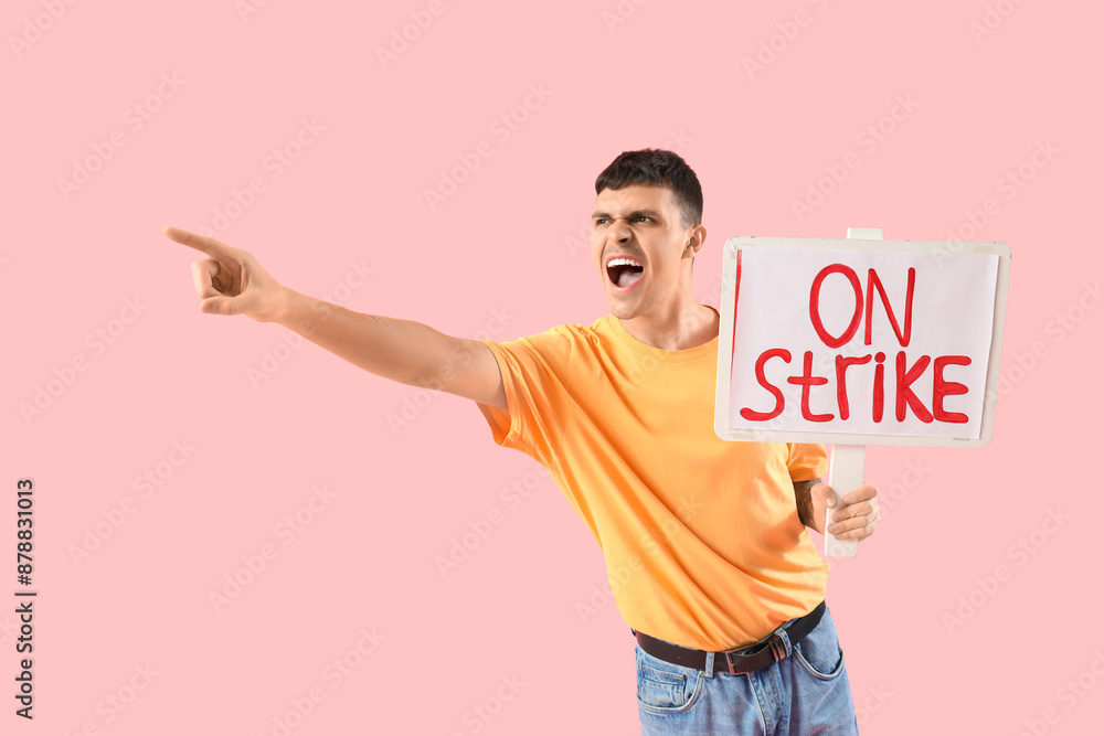 Protesting young man holding placard with text ON STRIKE and pointing ...