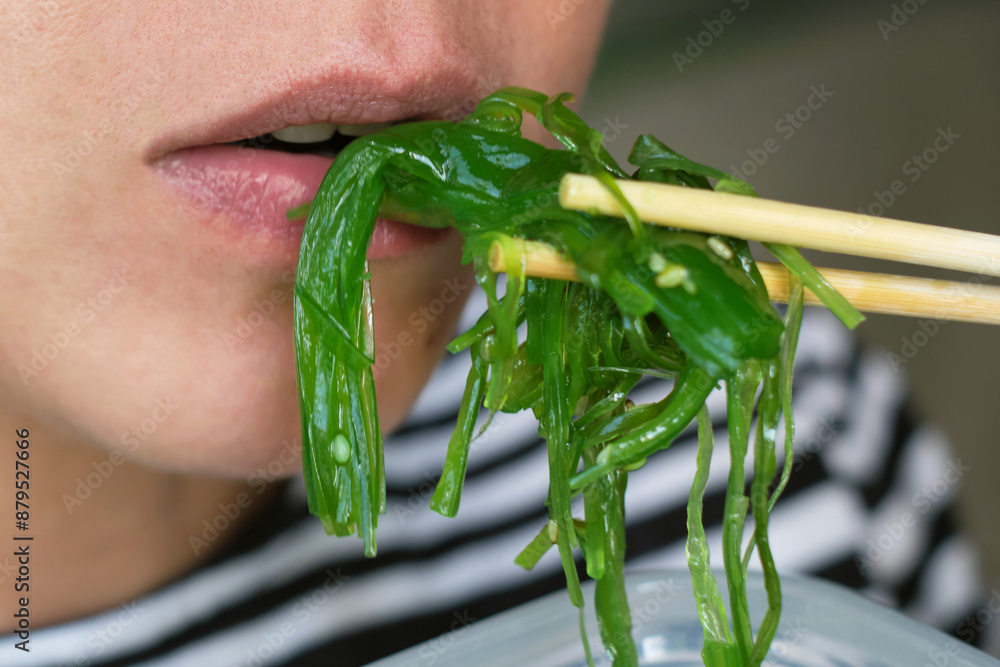 Mouth and hand of a person eating seaweed salad with chopsticks ...