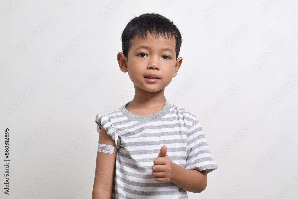Asian boy gives thumbs up and shows his arm with bandage after getting ...