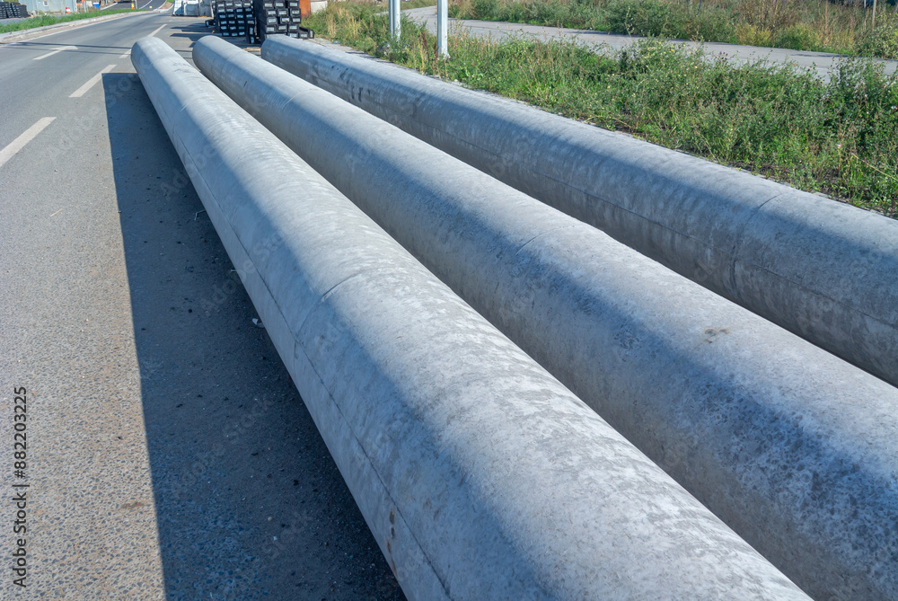 Reinforced concrete pipes lie on an asphalt road. Stormwater drainage ...