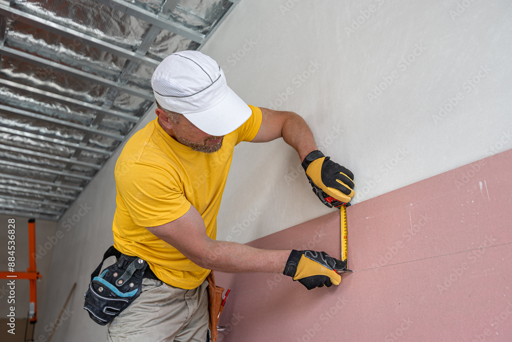 The worker make a plasterboard ceiling. He doing adjust a size of the ...
