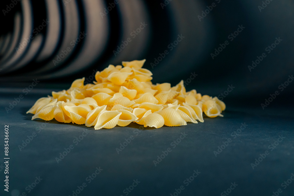 yellow vermicelli in the shape of shells lies on black and blue ...