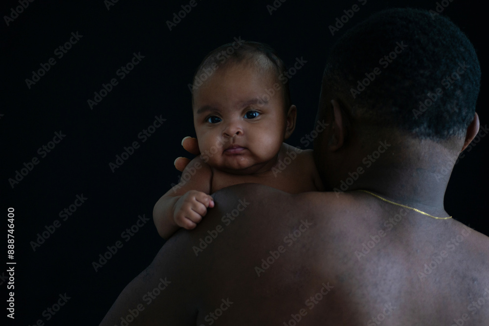 Shirtless African father holding his newborn baby girl on black ...