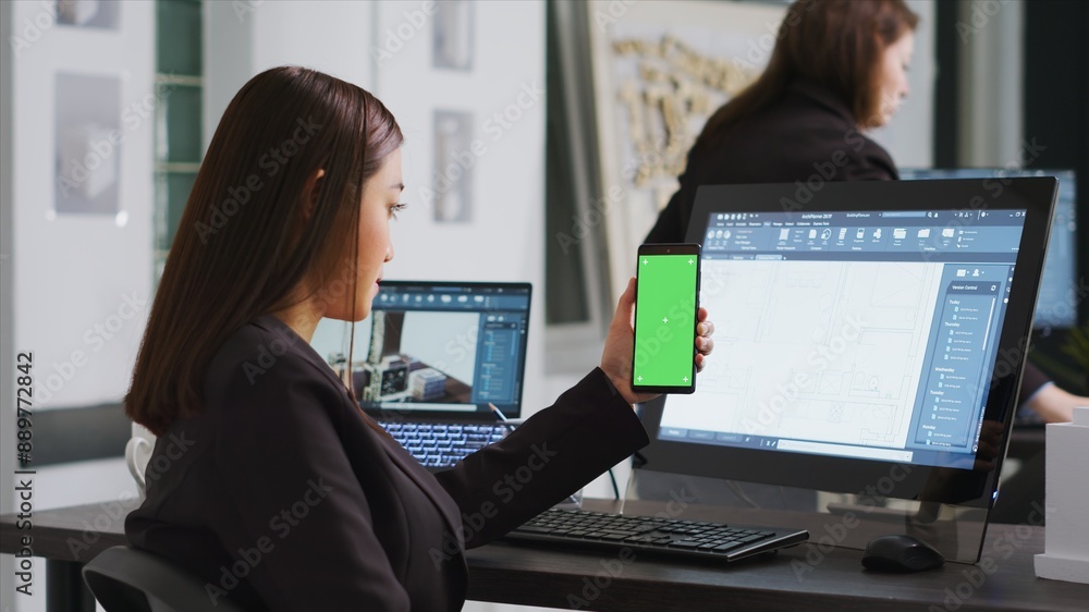 Engineer showing phone with greenscreen template on display, working at ...