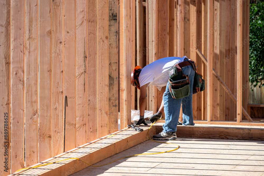 Construction worker in toolbelt and hard hat working with a hammer on ...
