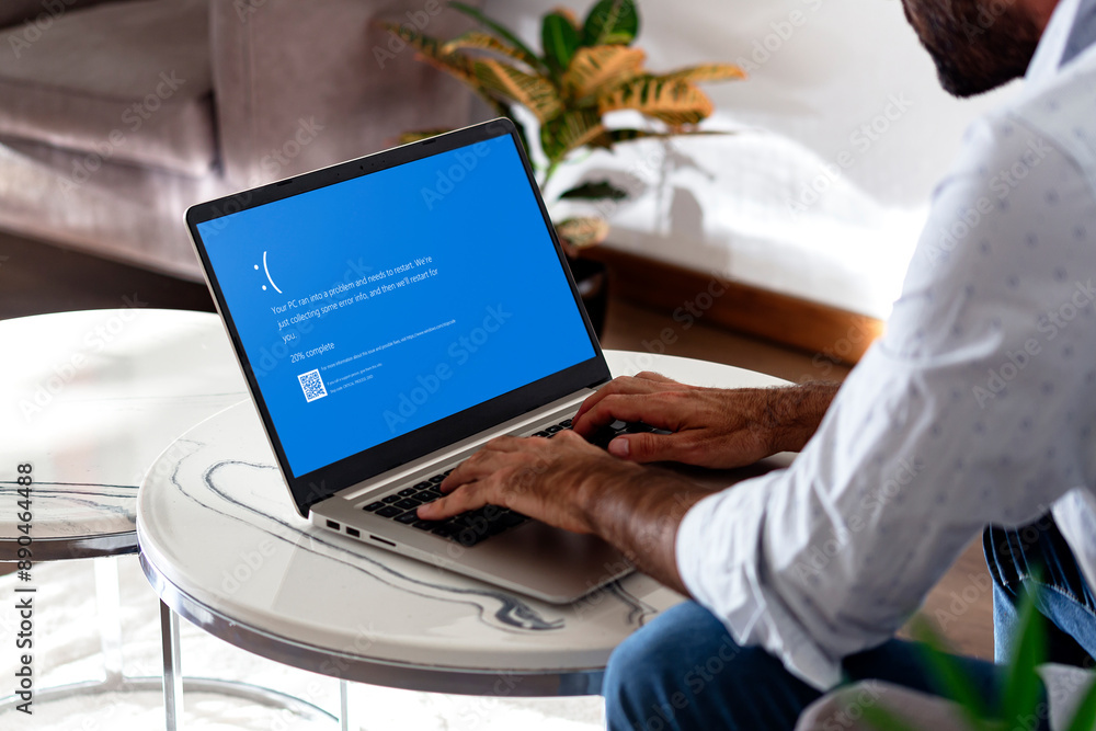Man with laptop showing Blue screen of death or BSOD on the monitor ...
