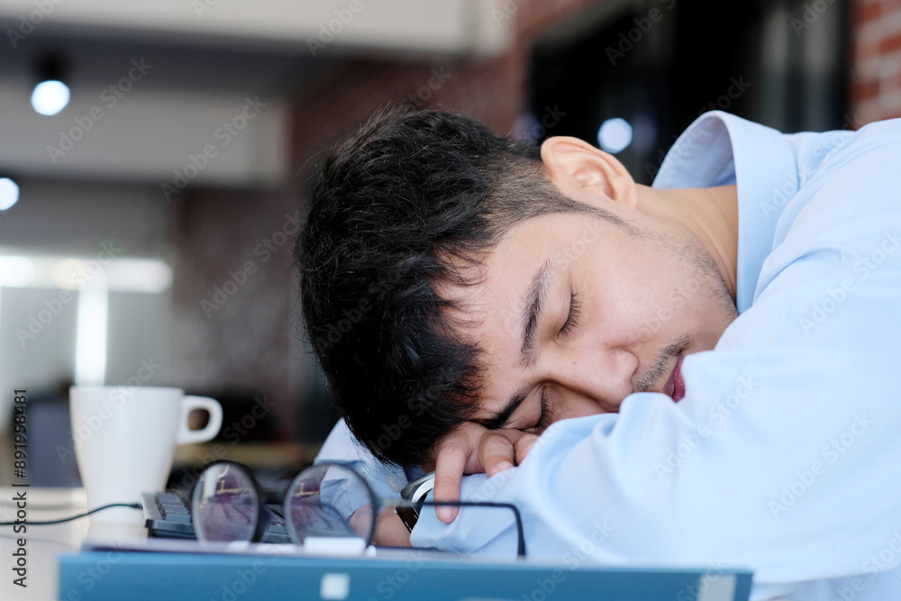 Tired asian man sleeping at office desk. Young businessman with ...