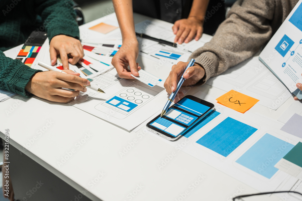 A group of people collaborates around a desk, discussing and reviewing ...