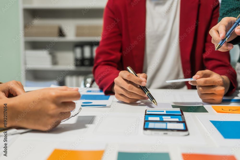 A group of people collaborates around a desk, discussing and reviewing ...