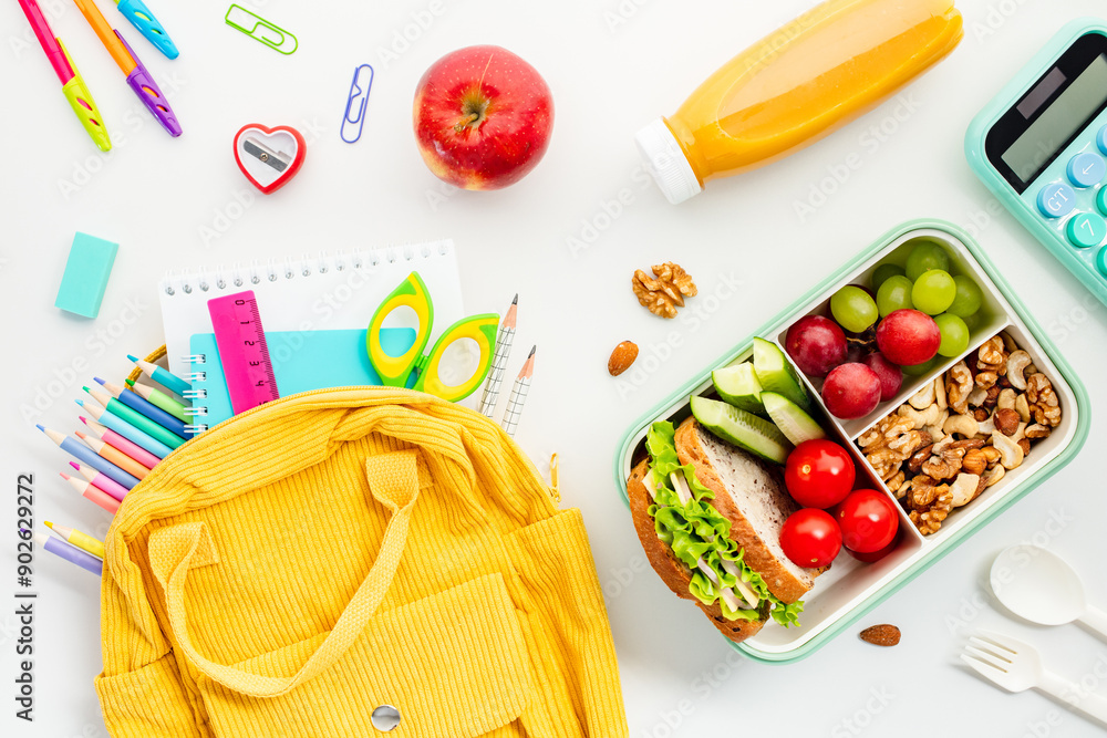 Flat lay yellow backpack, school supplies, a healthy lunchbox, and ...