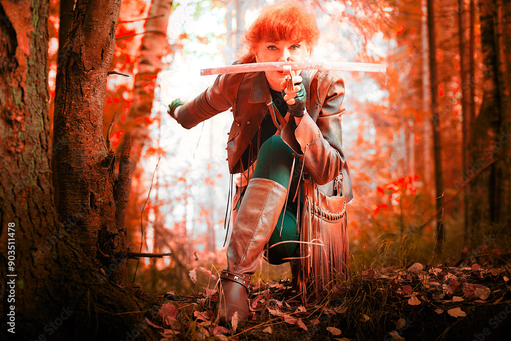Mature model portraying a royal huntress with red curve hair is hunting with a crossbow in the ...