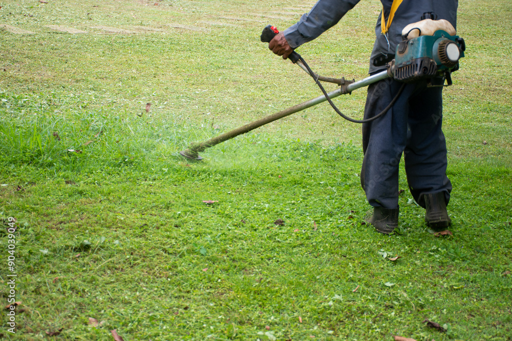 Gardener cutting grass in yard by using string trimmer. worker mows ...