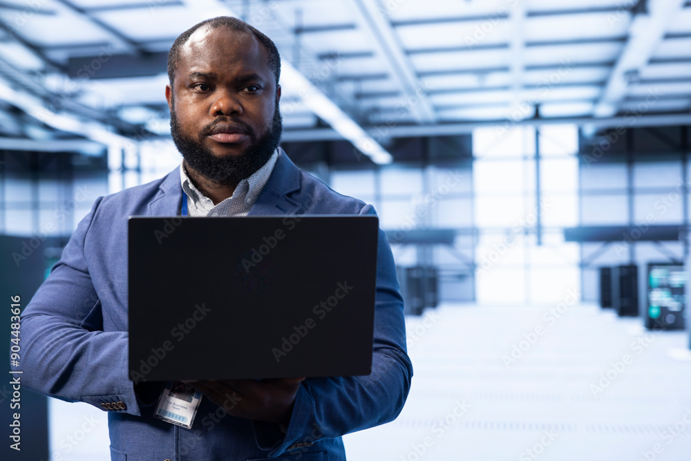 Programmer in data center using laptop to identify and solve technical issues related to data ...