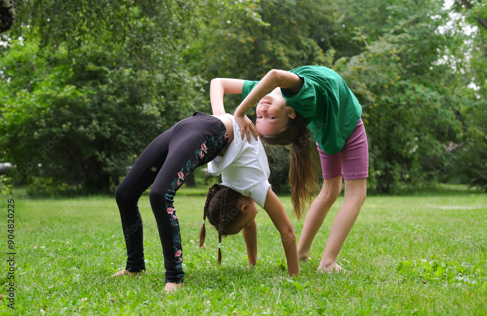 Teenage girls doing gymnastics in park, building bridge, arching their ...