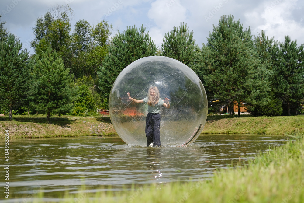 Aqua zorbing on water. A girl in a transparent balloon on the water ...