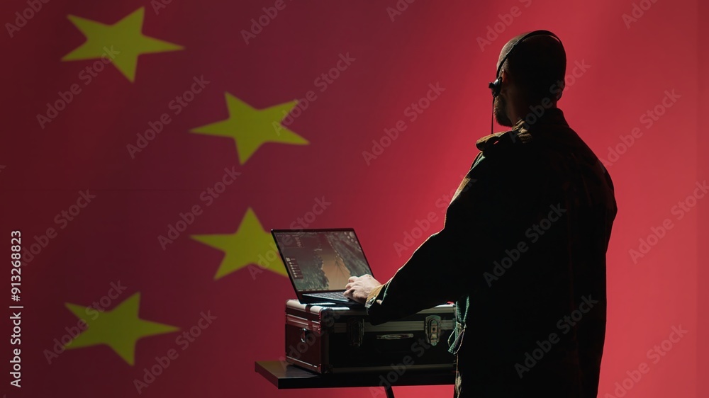 Chinese army military dispatcher looking at surveillance transmission on laptop, relaying ...
