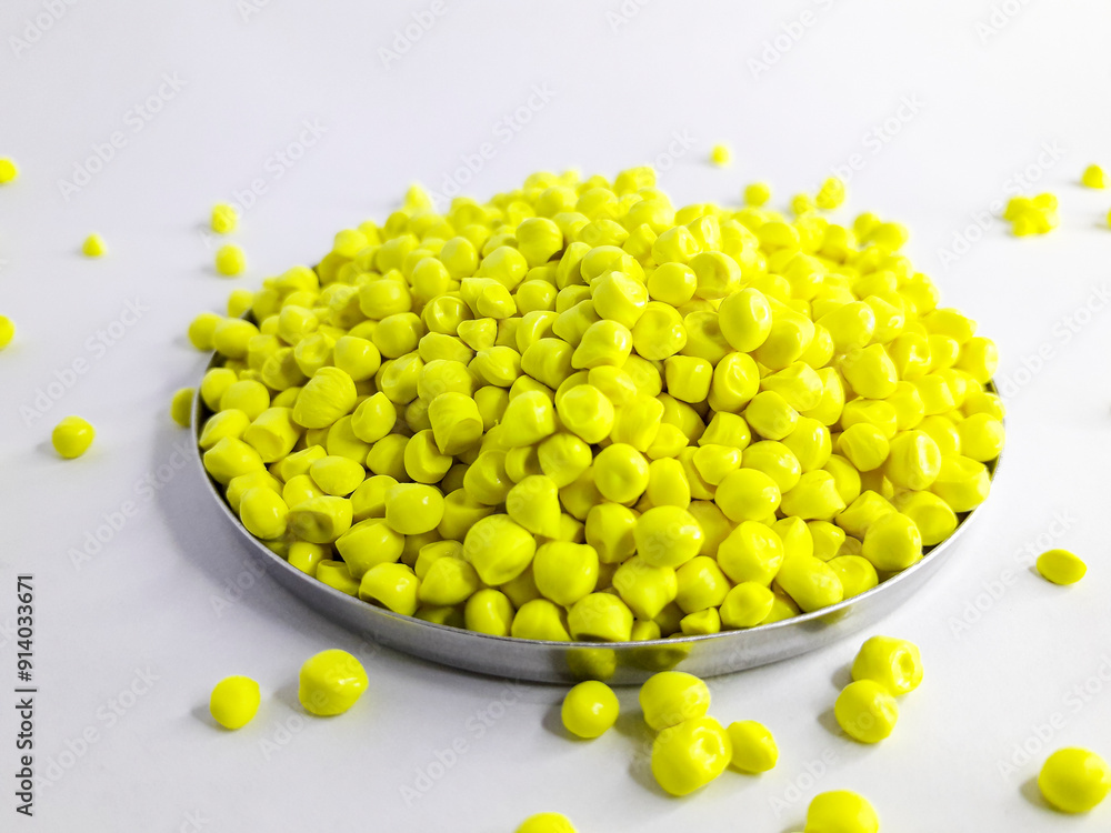 Neon yellow masterbatch granules in a dish isolated on white background ...