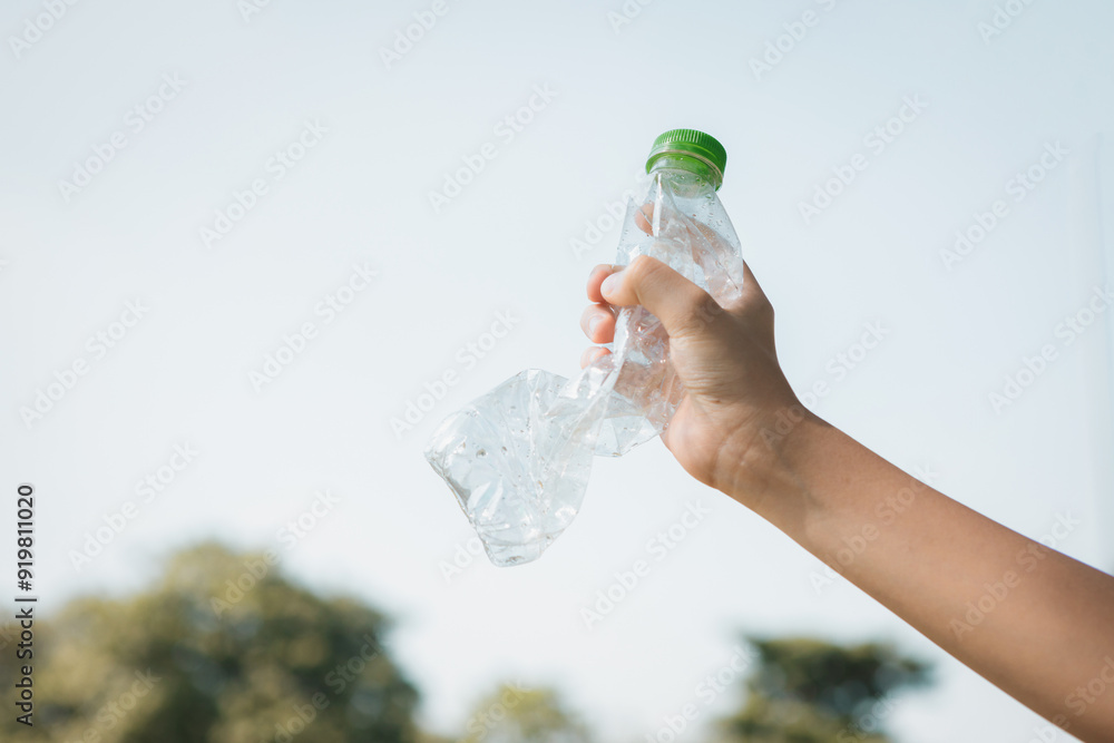 Recyclable plastic bottle held in hand up on sky background. Hand ...