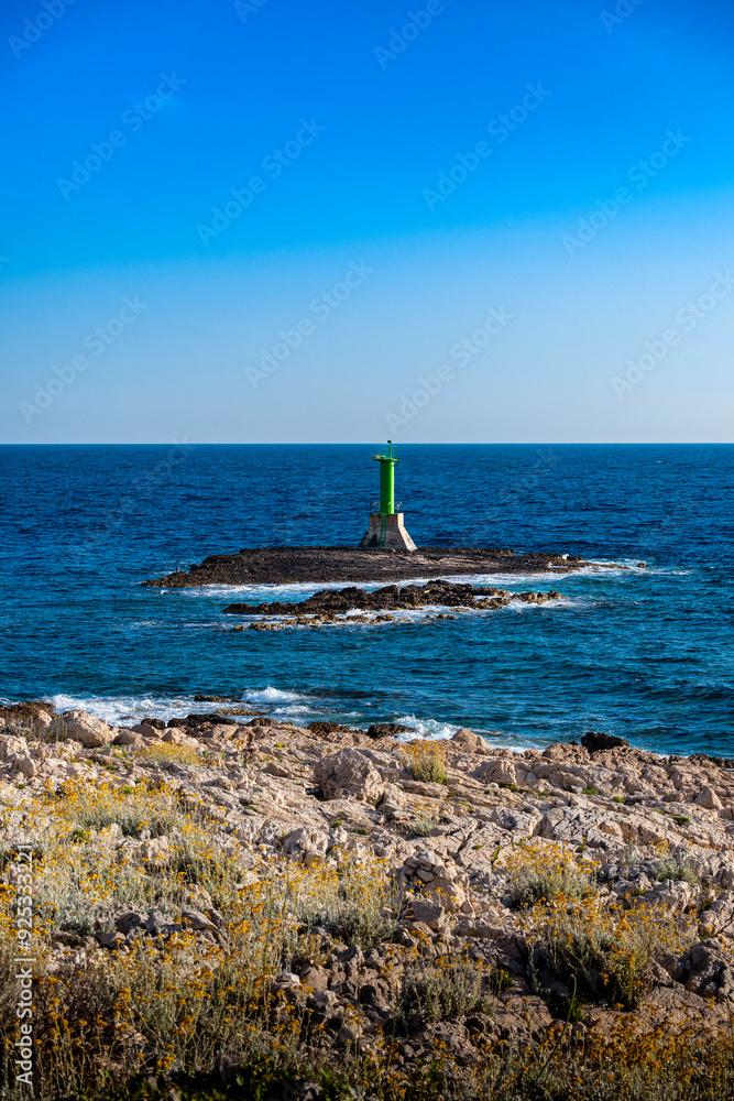 Green lighthouse on the rock in front of Punta Planka cape on the most ...