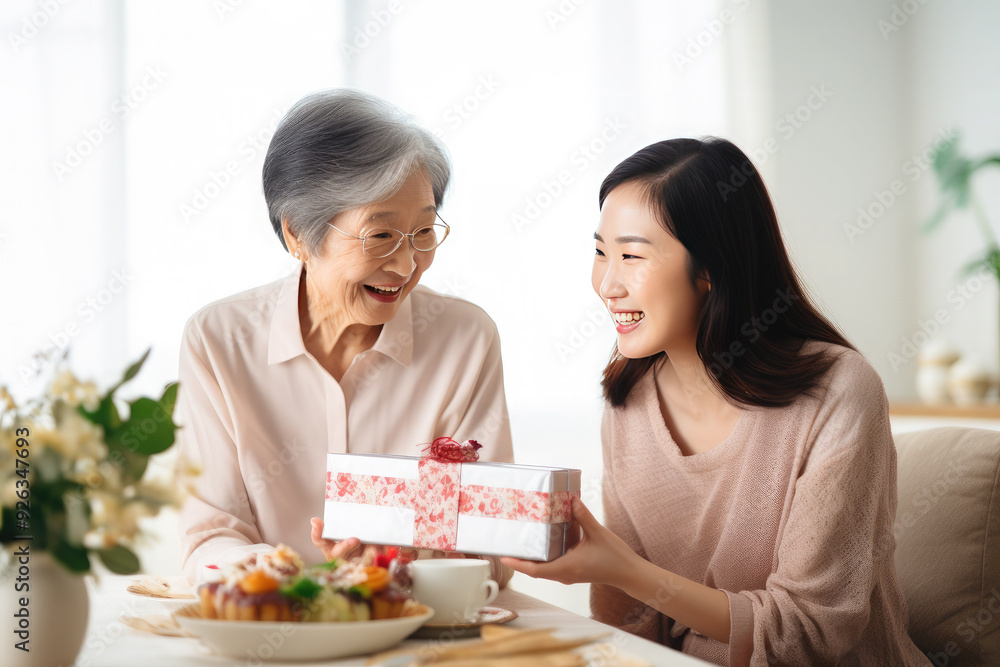 Granddaughter is giving a gift to her happy grandmother for keiro no hi, the japanese holiday ...