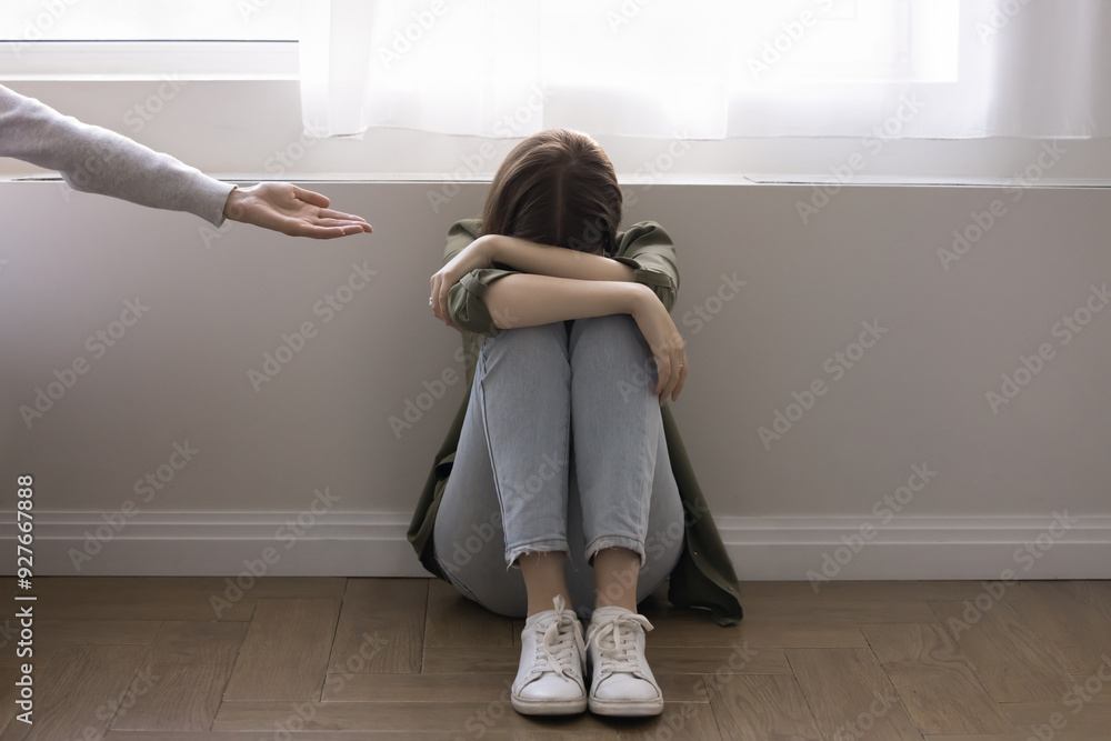 Girl crying seated on floor, mother hand extended to her like symbol of ...