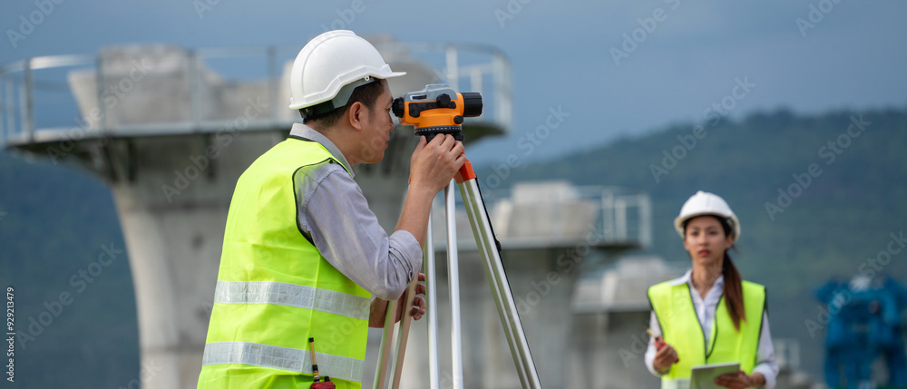 Survey team is working with a theodolite and road construction plans ...