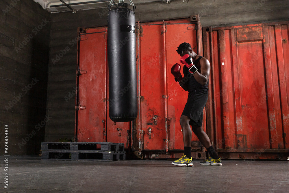 Powerful African American boxer wearing red gloves prepares to hit ...
